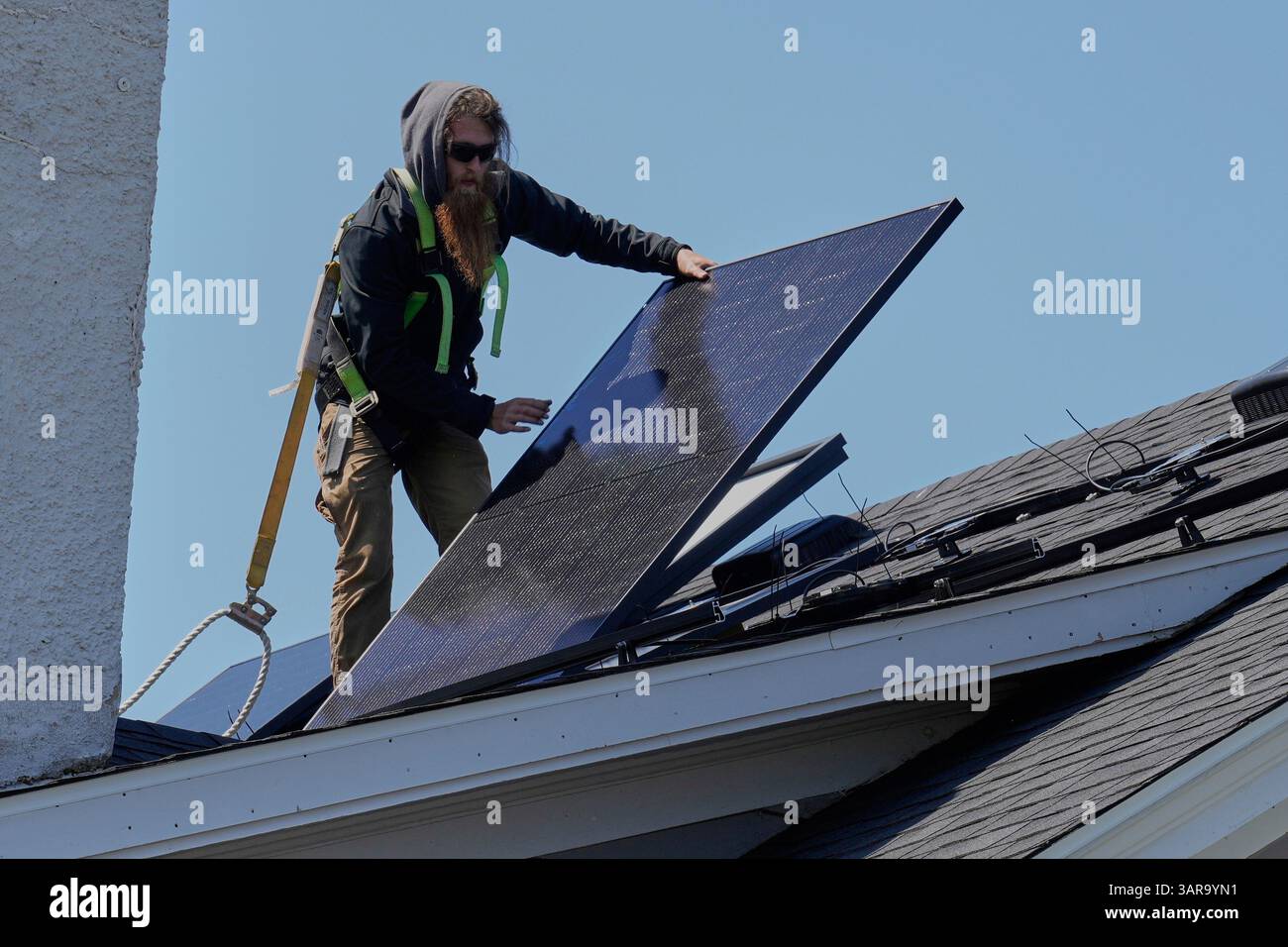 Theodore Tanczuk, of solar installer YellowLite, puts a panel on a roof ...