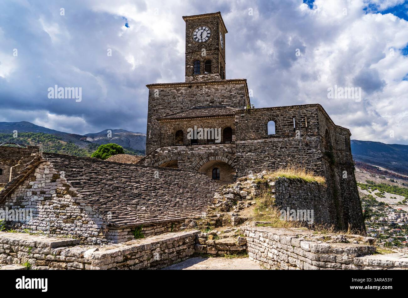 A historic stone clock tower stands prominently against a dramatic sky ...