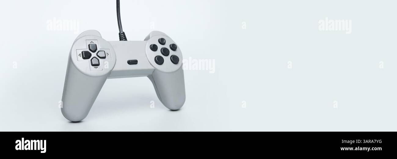 Close-up of retro wired video game controller against pale background ...