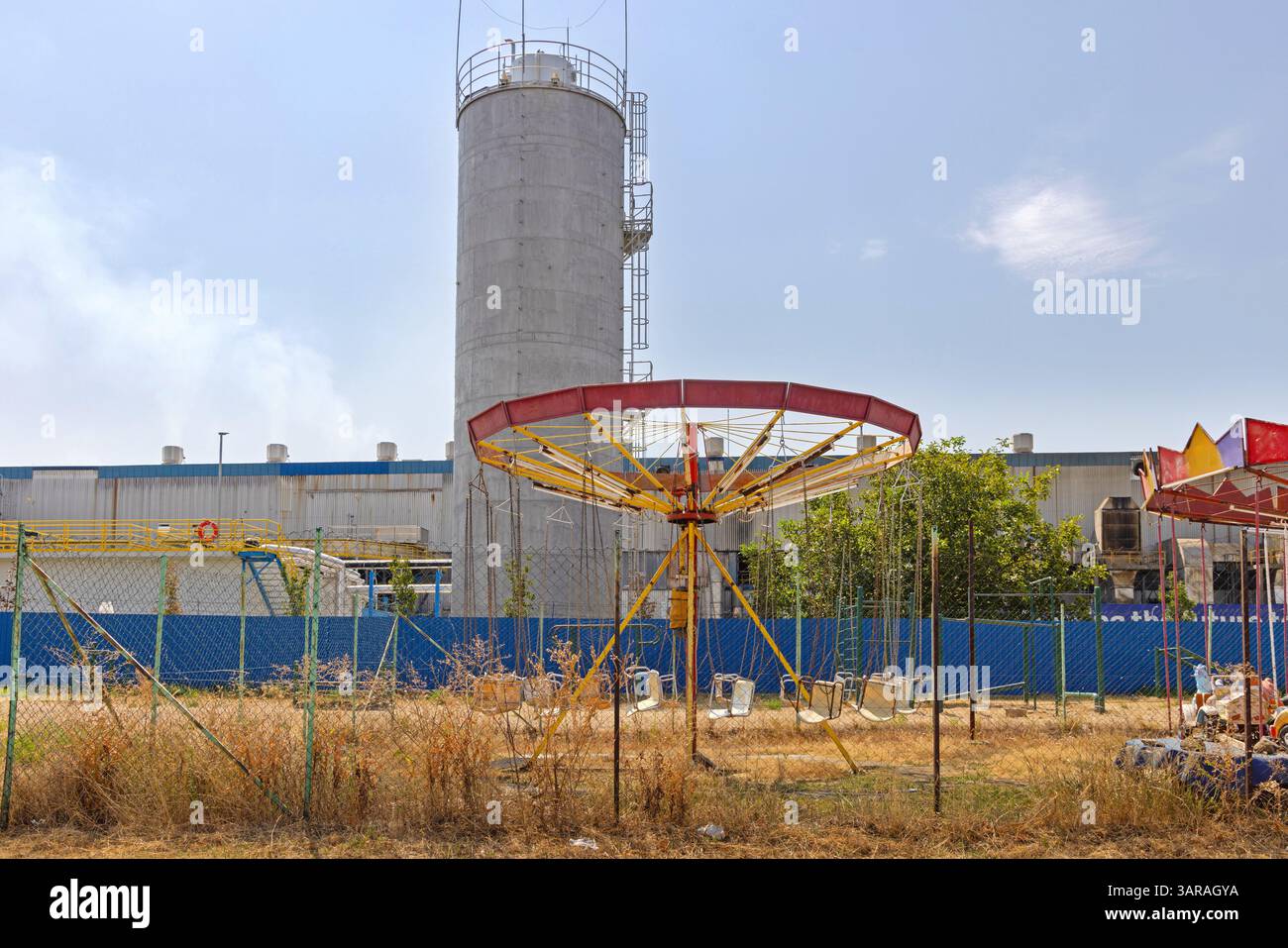 Abandoned Carousel Ride for Children at Park Behind Large Silo Factory ...