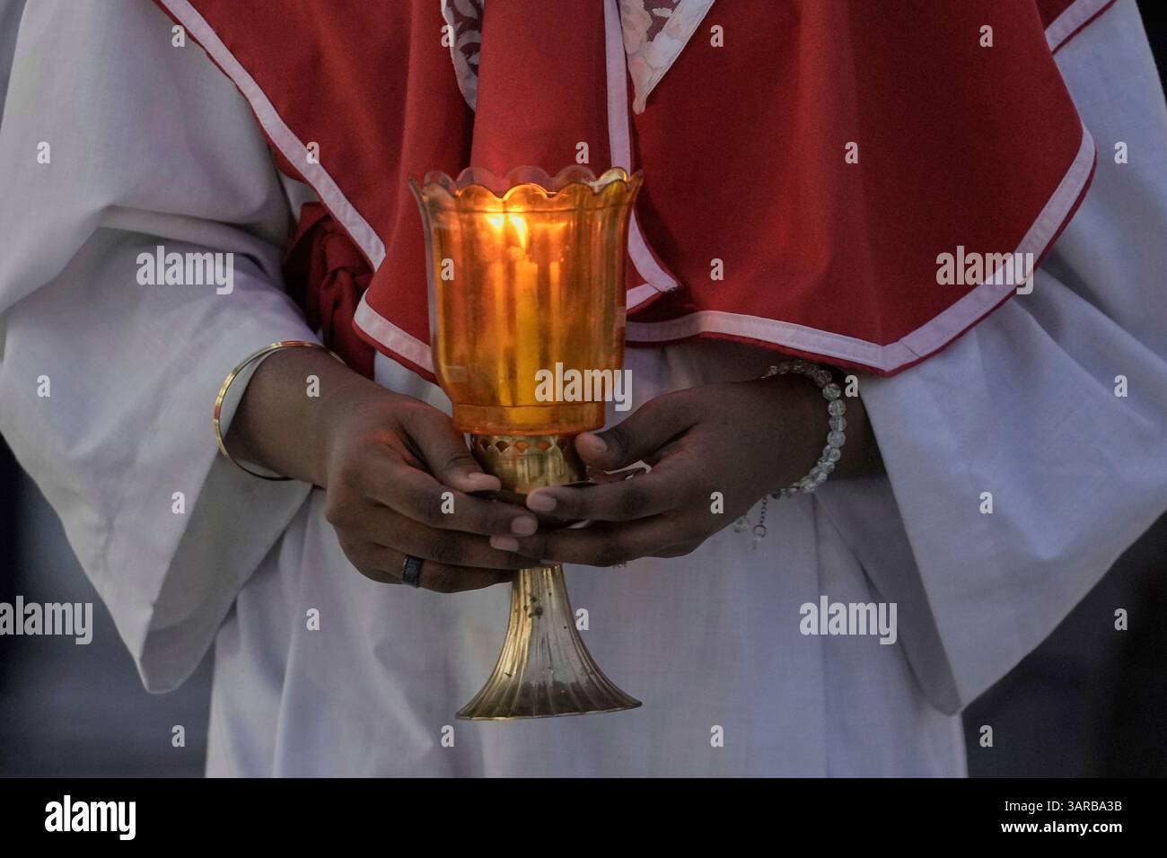 An altar girl holds a candle as she walk towards the altar during a ...