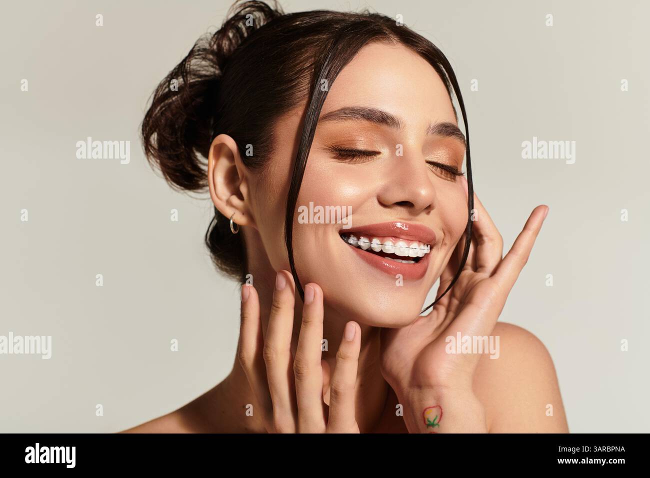 A young woman joyfully displays her radiant smile in an elegant studio ...