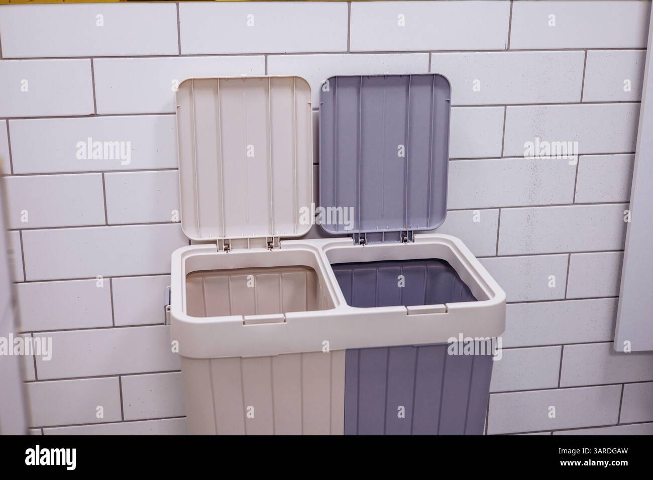 A contemporary kitchen features a dual compartment waste bin designed ...