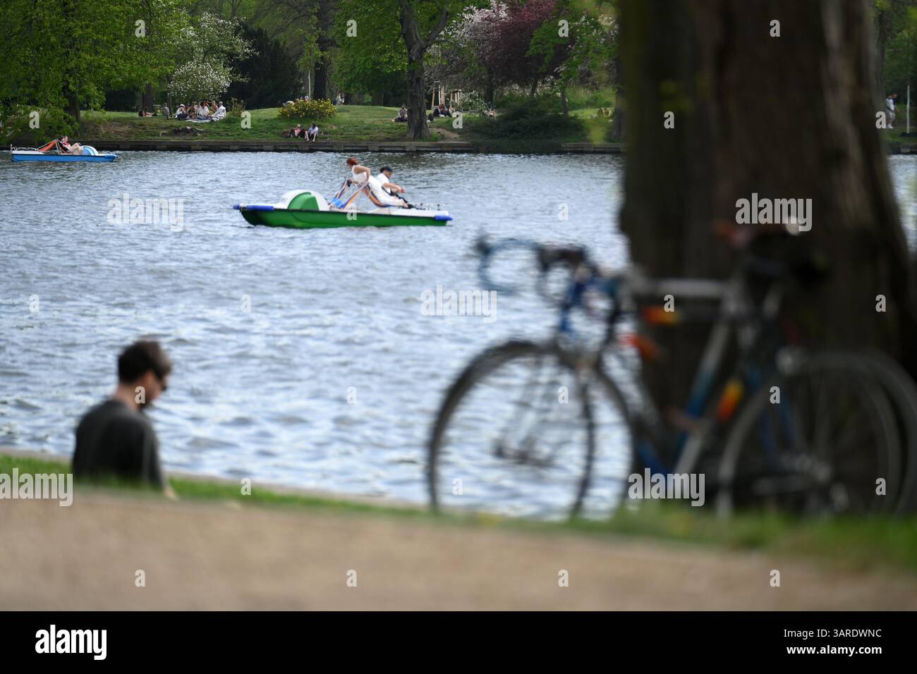17 April 2025, Berlin: A man sits on the banks of the Spree in Berlin ...