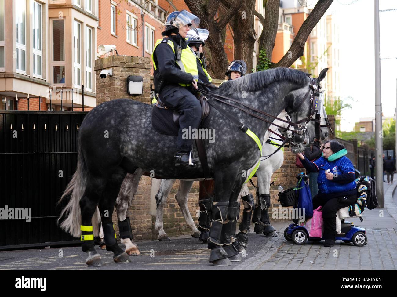 A Chelsea fan approaches a police horse patrol near Stamford Bridge ...