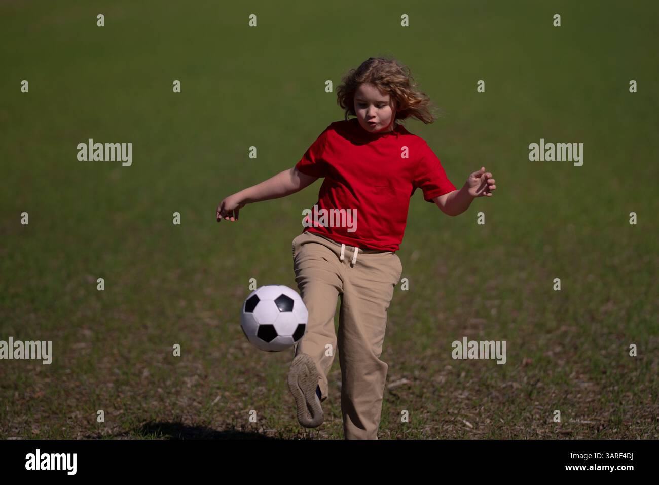 A kid is playing football. A child kicks the soccer ball. Kids sport ...