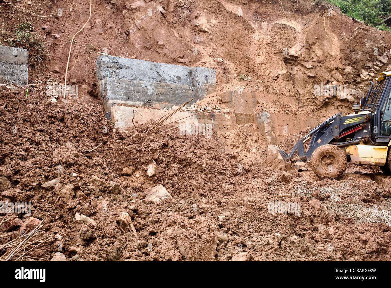 Excavator clearing debris at a hillside construction site in ...