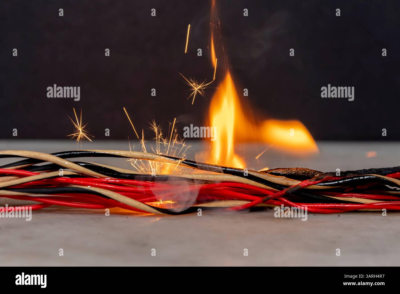 Twisted electrical wiring burns and smokes on a dark background. Short ...