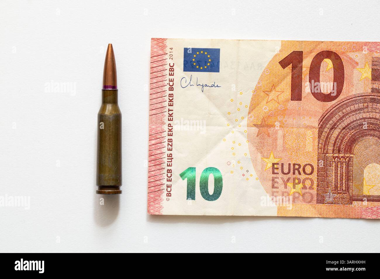 A bullet lies next to a ten euro bill on a white background, money for ...