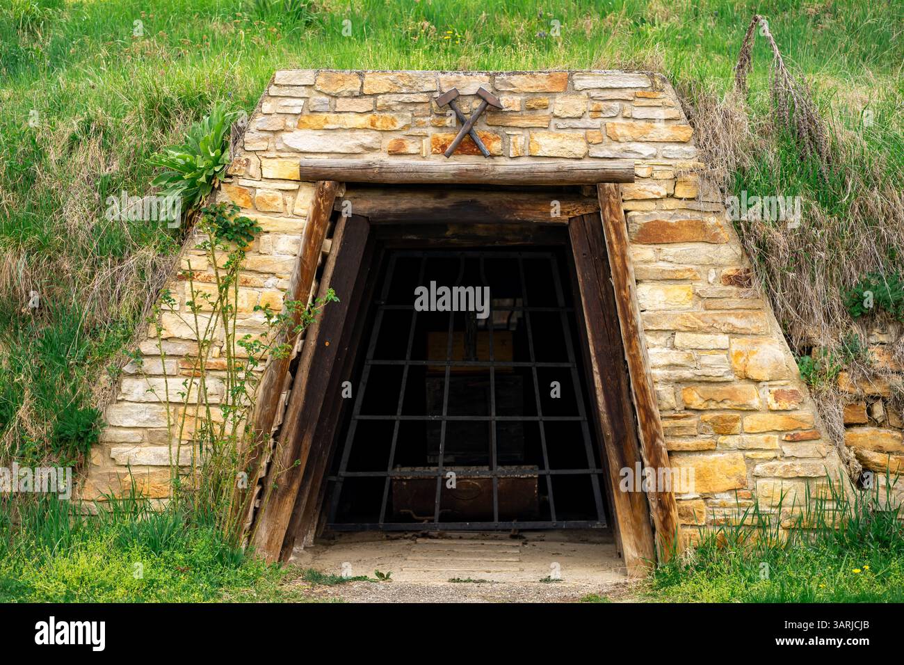 View of the entrance to an old stone mine covered with a steel grate ...