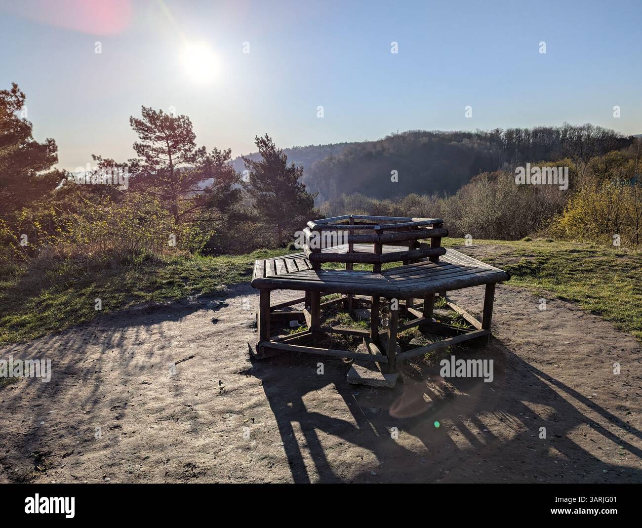 A sturdy wooden bench is placed on a rustic dirt road, surrounded by ...