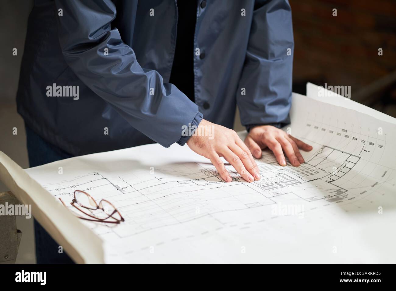 Unrecognizable builder looking at large piece of paper with detailed ...
