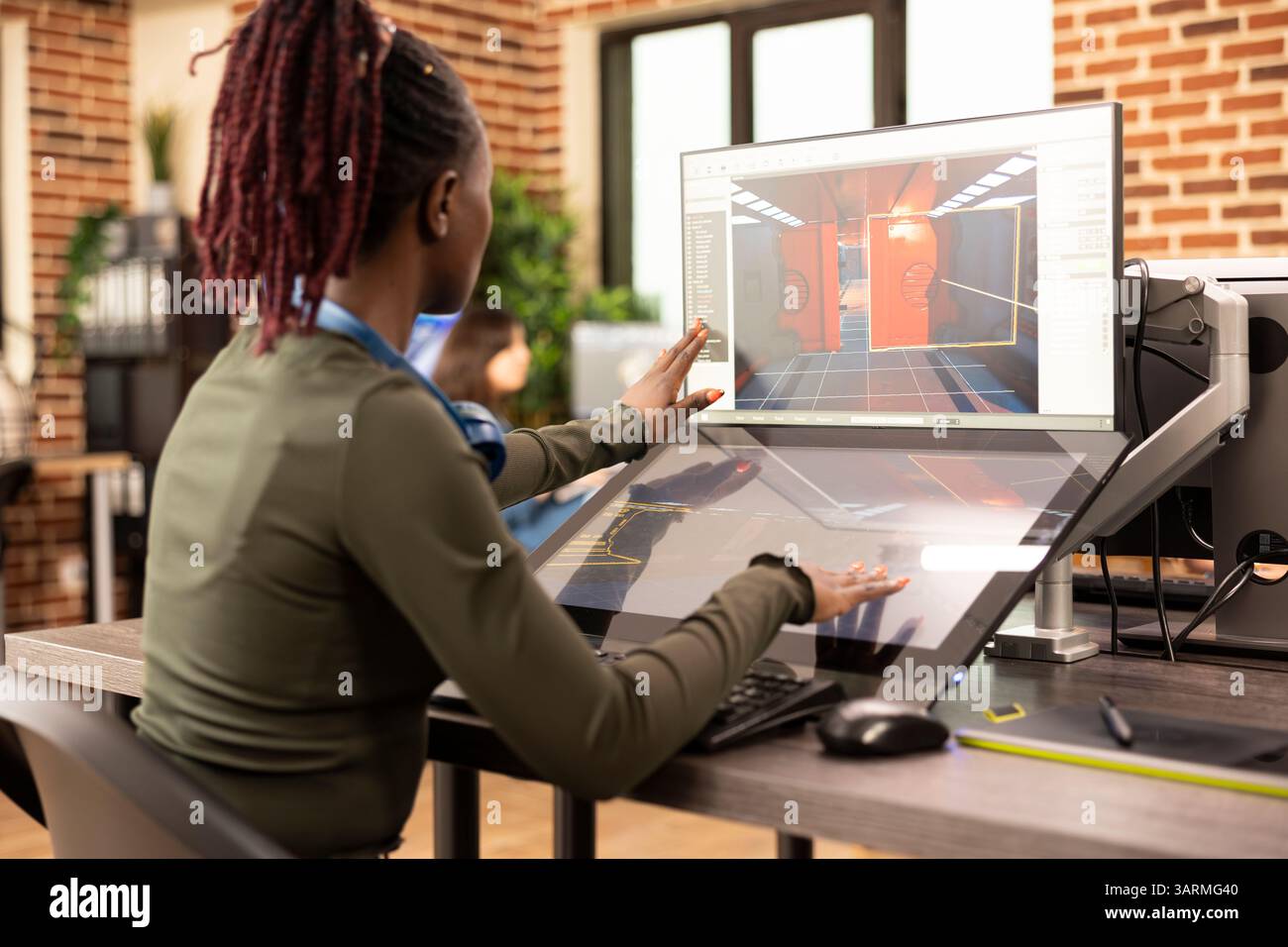 African American designer refining projects on digital monitors ...