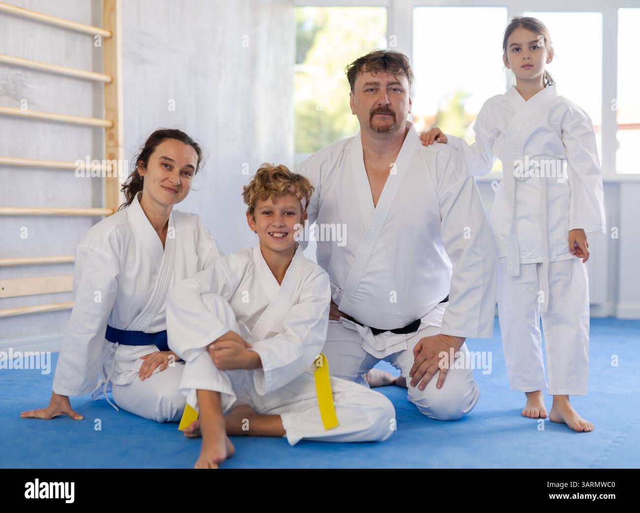 Friendly sporty family with tween children in kimonos posing in gym ...