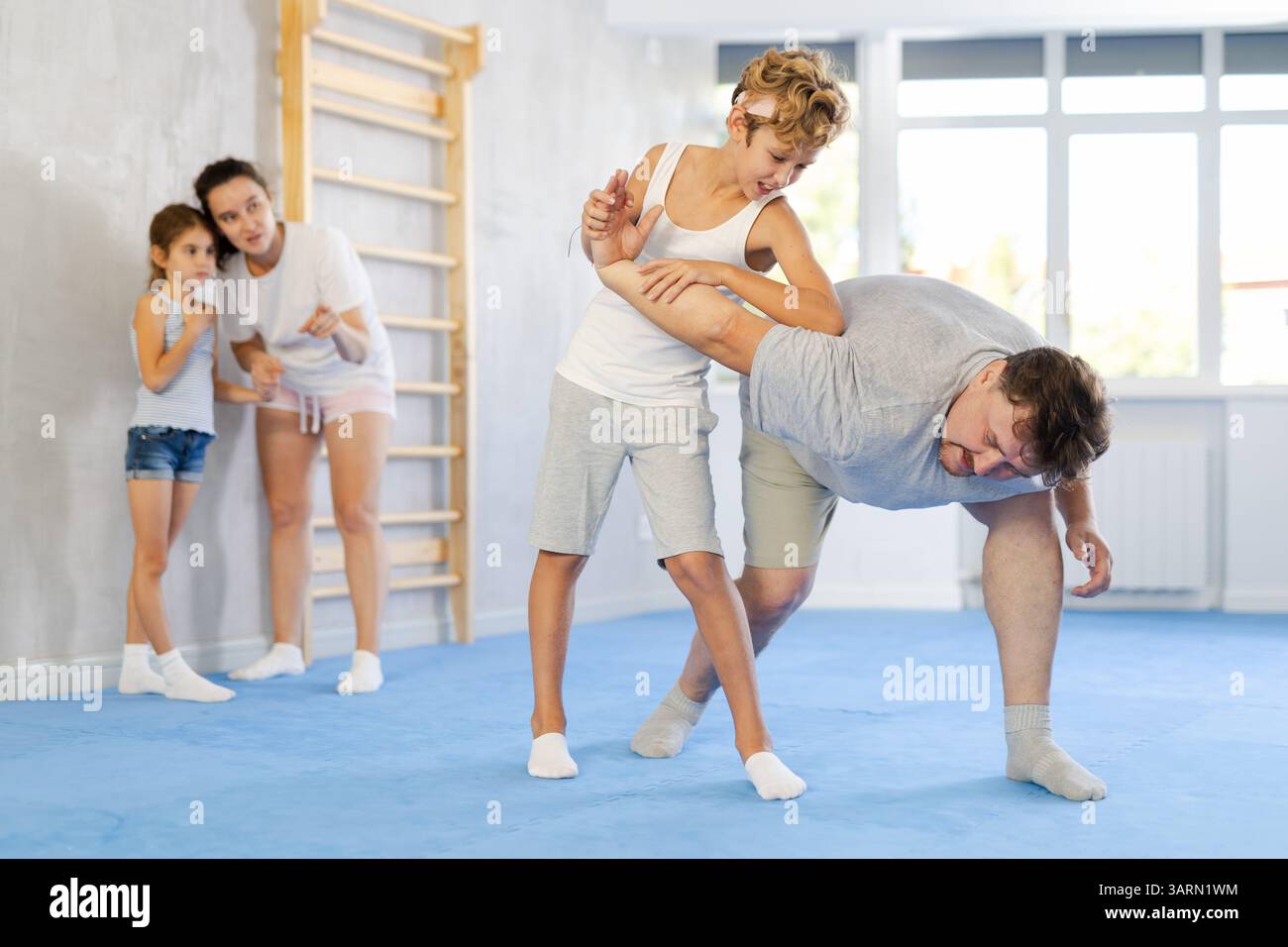 Father teaches his son to use forceful techniques and grips during self defense classes Stock ...