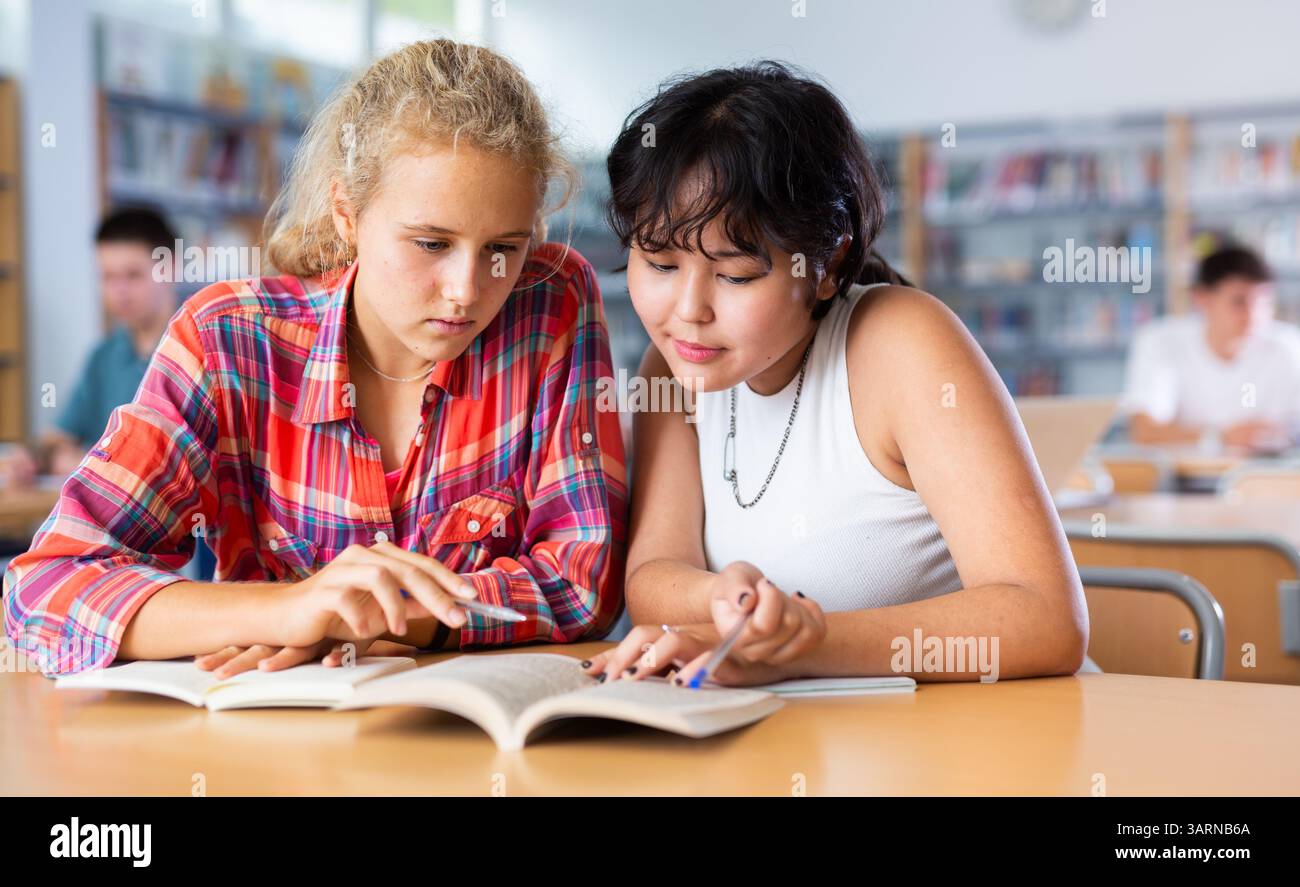 Two schoolgirls reading books and taking abstract in copybooks Stock ...
