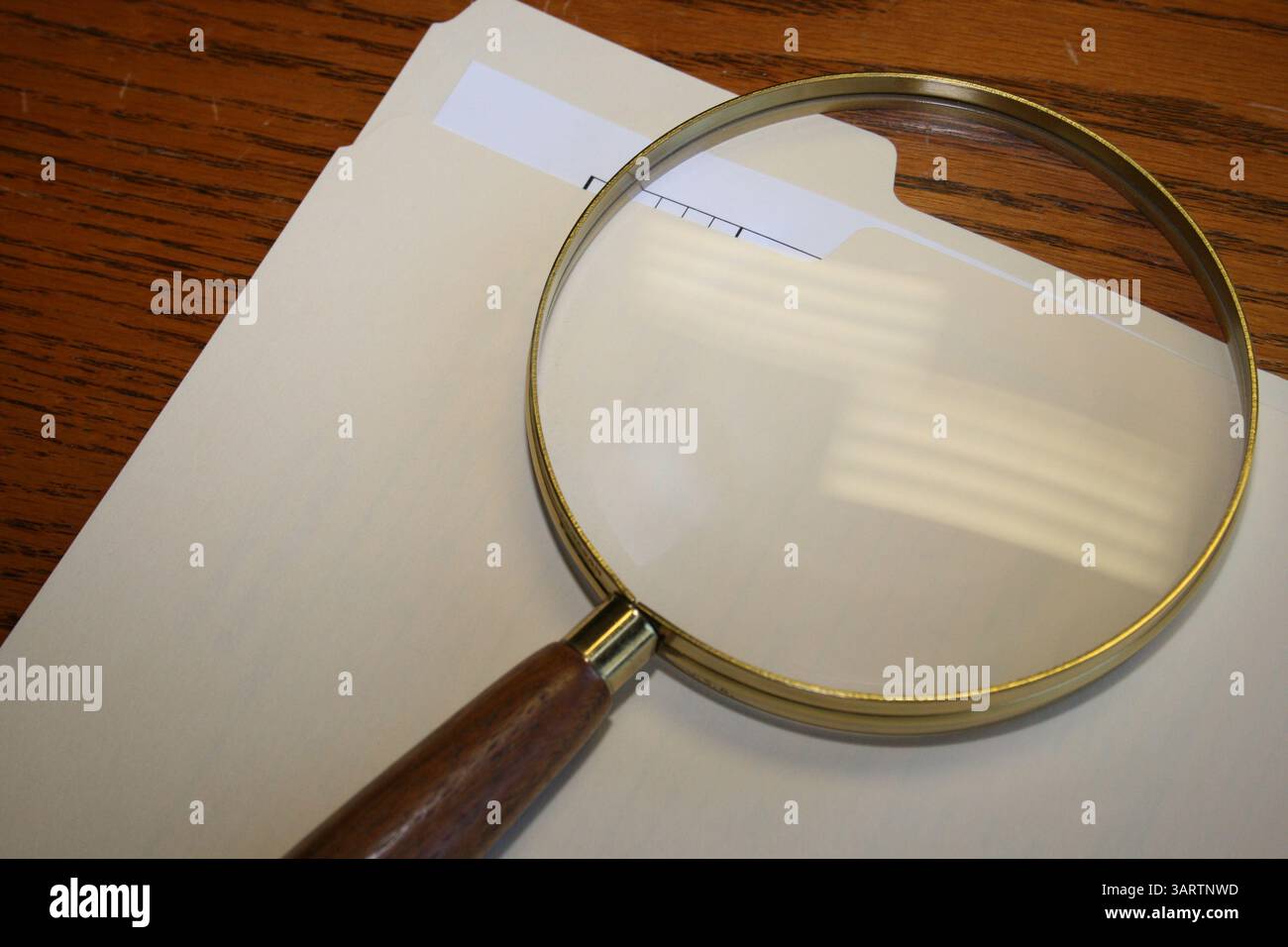 A magnifying glass and file folder on a desk Stock Photo - Alamy