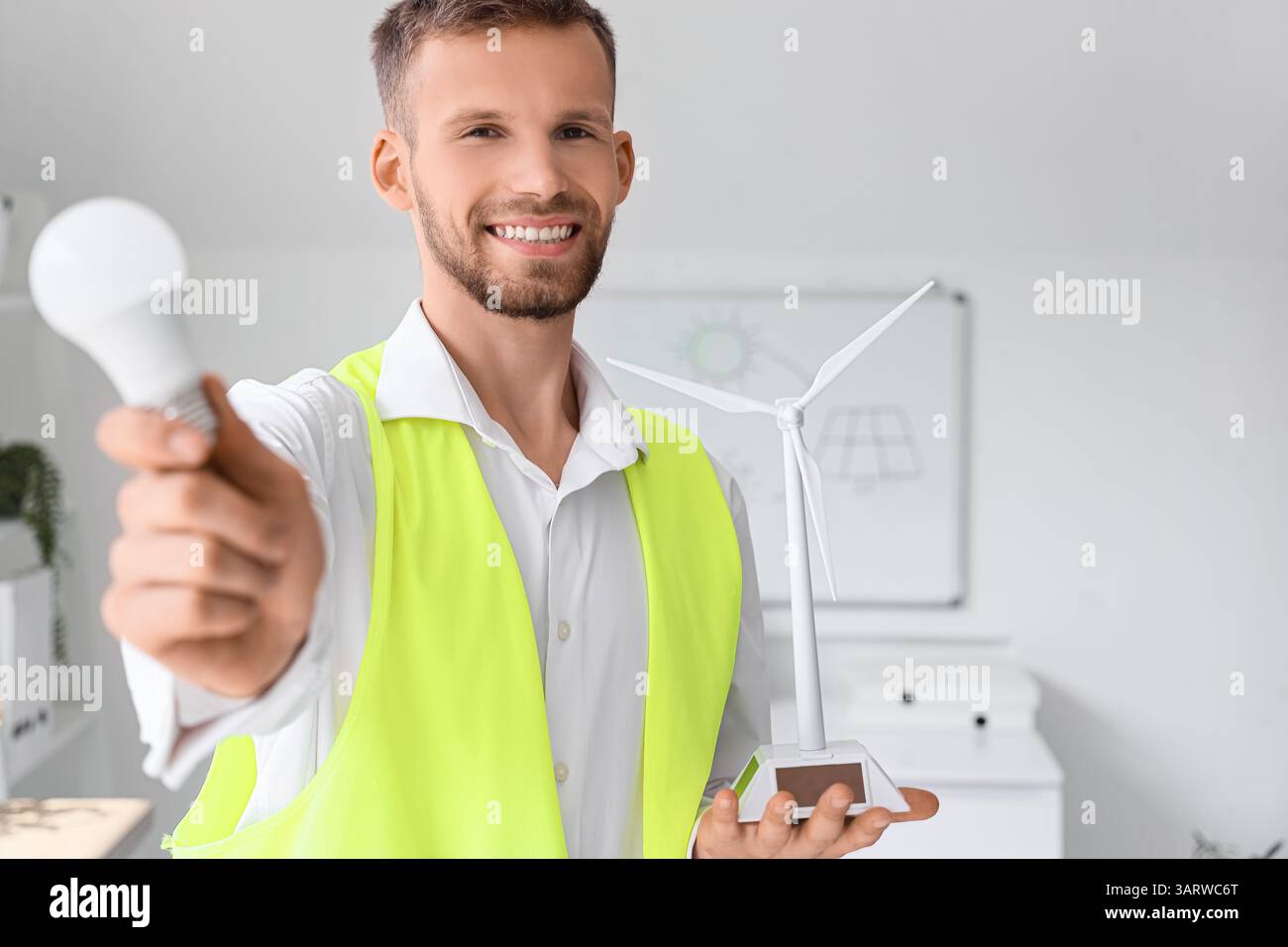 Male engineer with wind turbine model and light bulb in office Stock ...