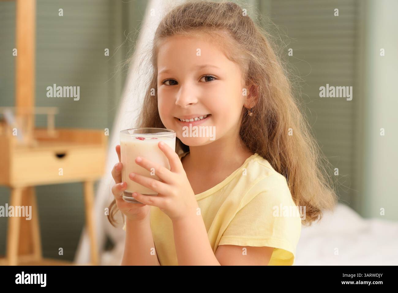 Cute little girl with glass of yogurt in room Stock Photo - Alamy