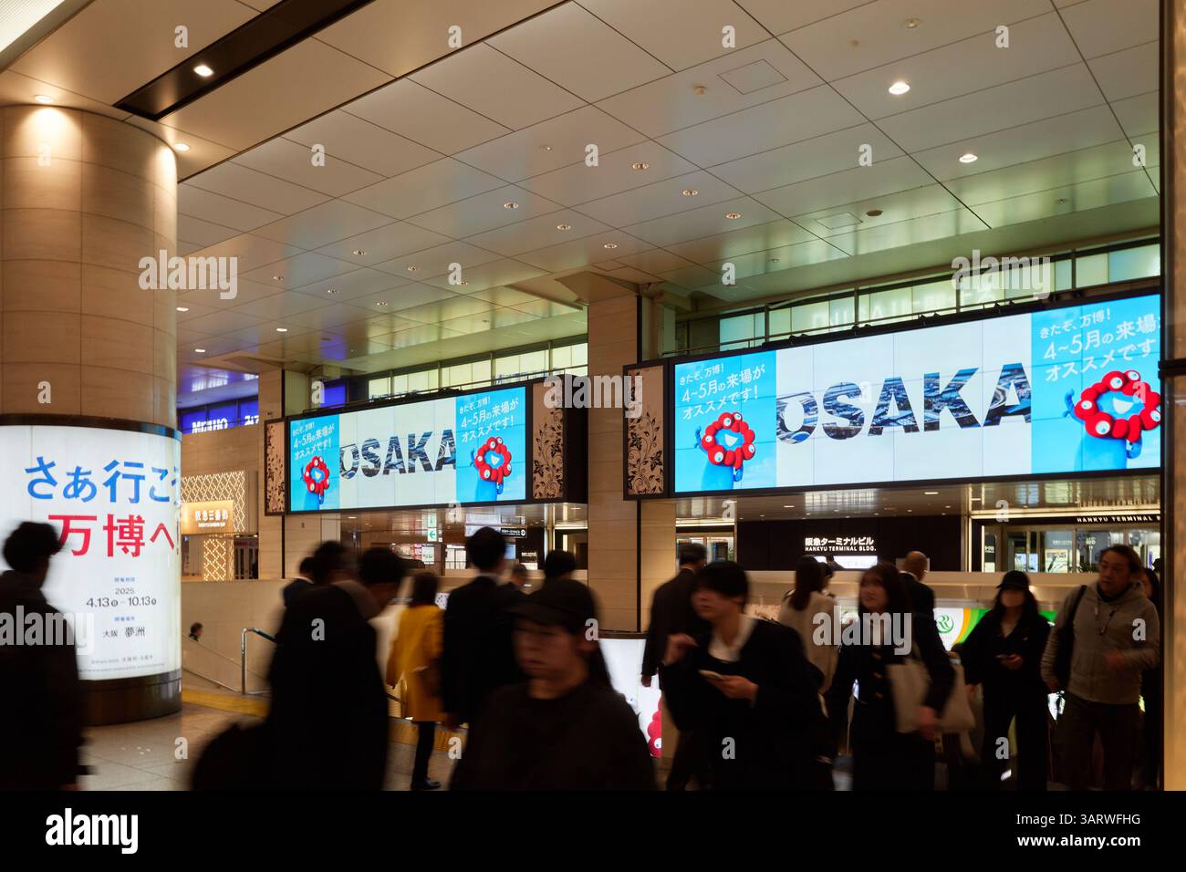 Pedestrians pass advertisements for the 2025 World Expo displayed in Hankyu Umeda Station, Osaka ...