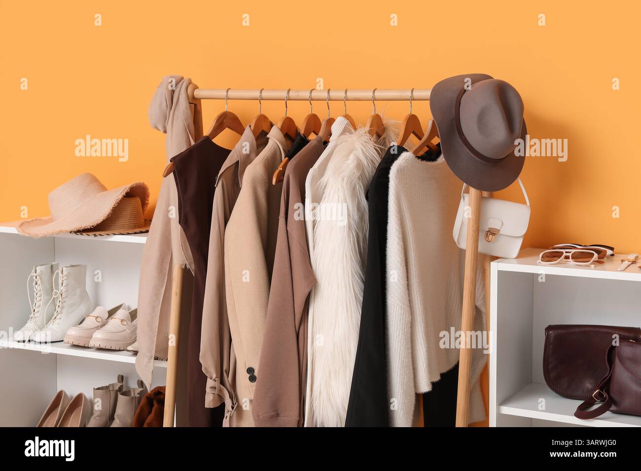 Stylish female clothes hanging on rack, shelving unit with shoes and ...