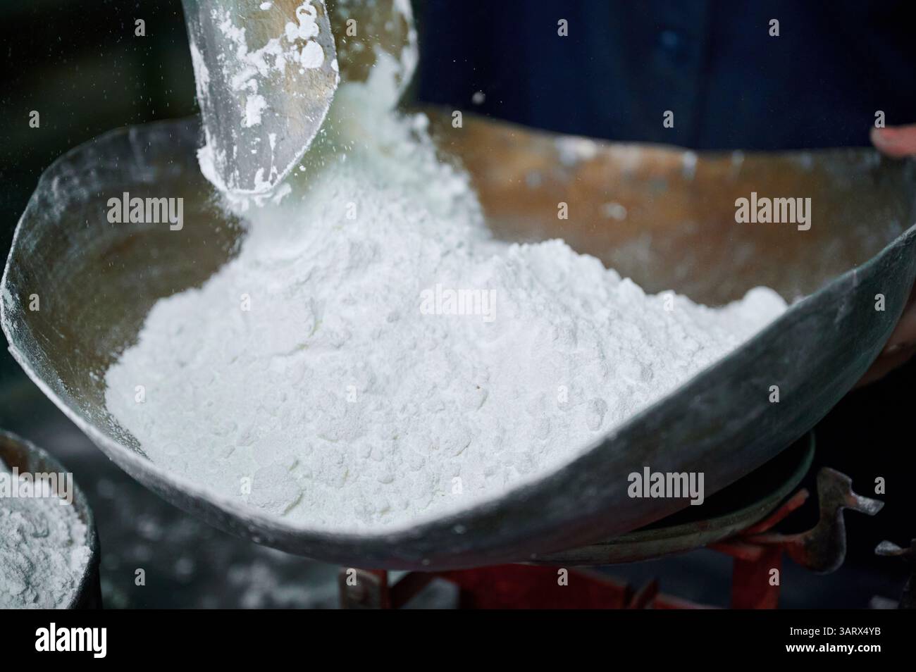 Pouring fine white powder into a traditional scale for precise ...