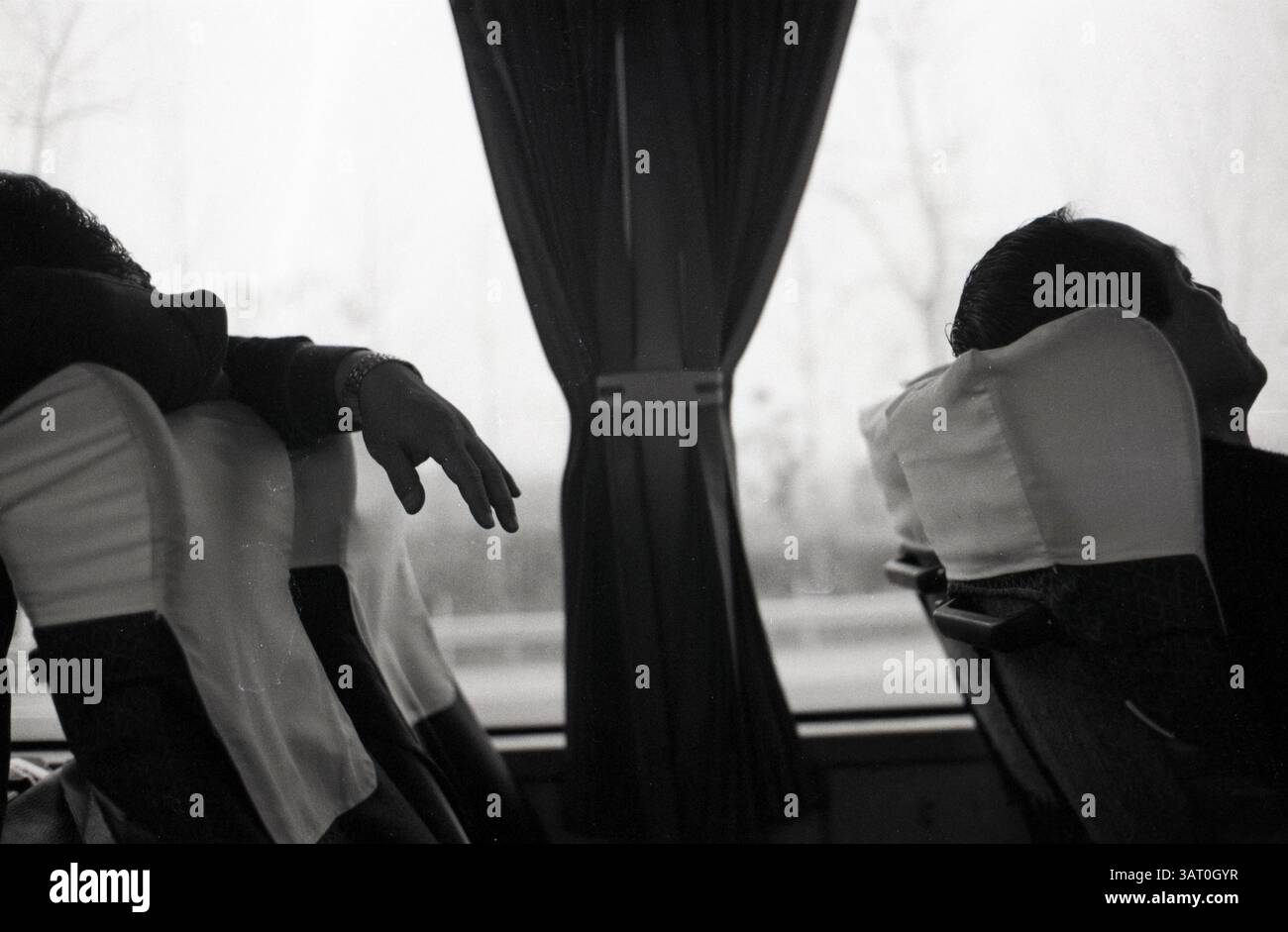 Two travelers relaxing on a bus journey through misty landscapes during ...