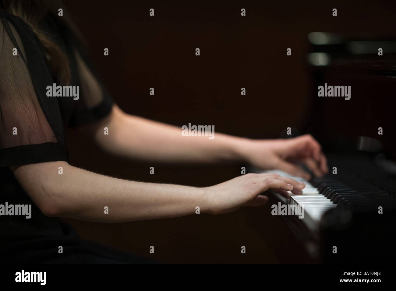 Hands and arms of a young pianist playing on the keyboard of a Steinway ...