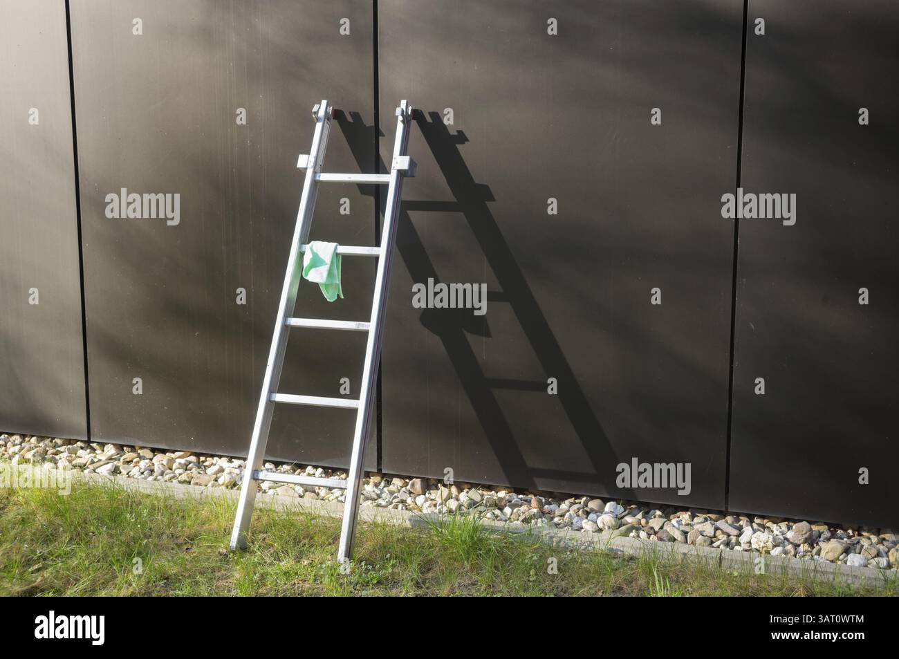 Metal ladder is leaning against a modern building with a cleaning cloth ...