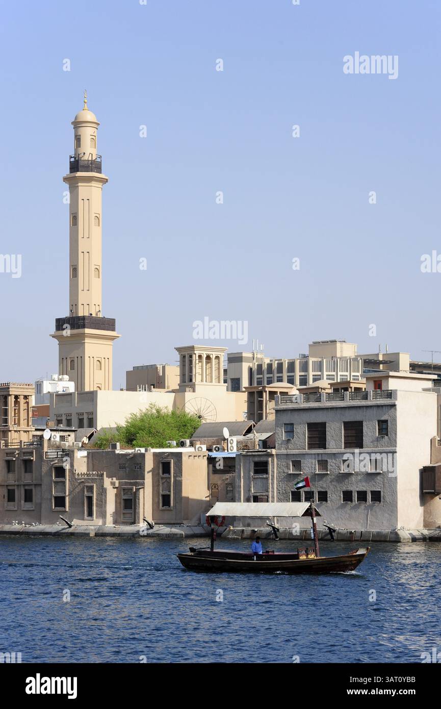 Boat on the Dubai Creek estuary, behind it the minaret of the Grand ...
