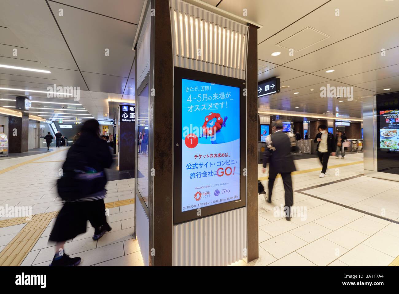 Pedestrians walk past advertisements for the 2025 World Expo displayed ...