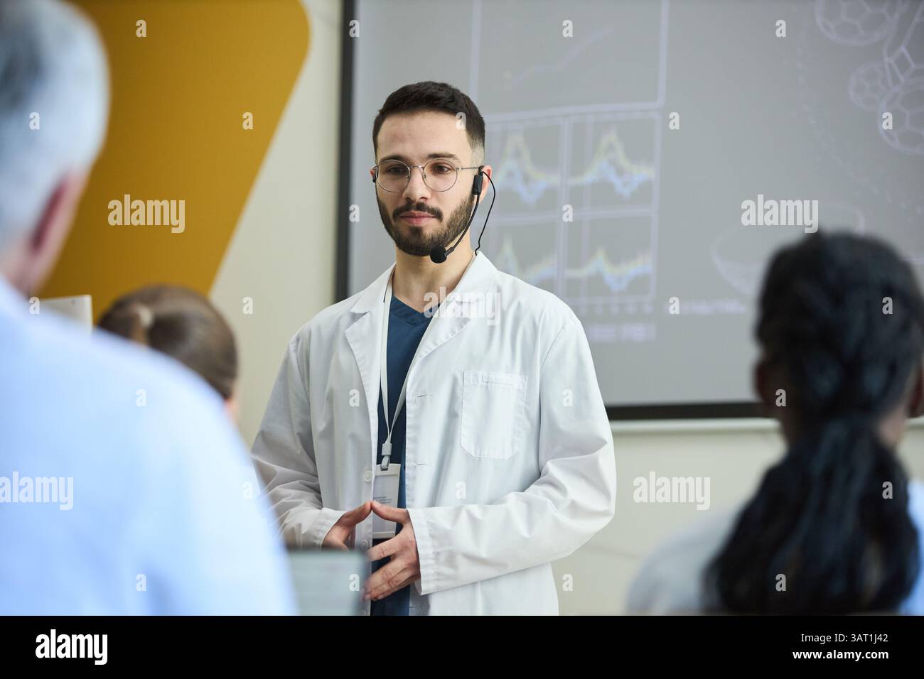 Medical professional in white lab coat engaging with audience during ...