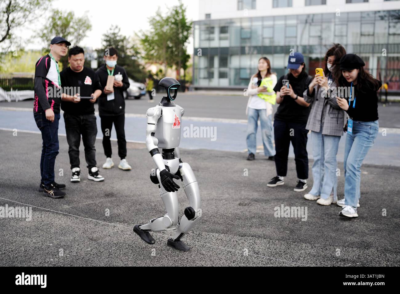 Beijing,China.17th April 2025. People take photos of a humanoid robot ...