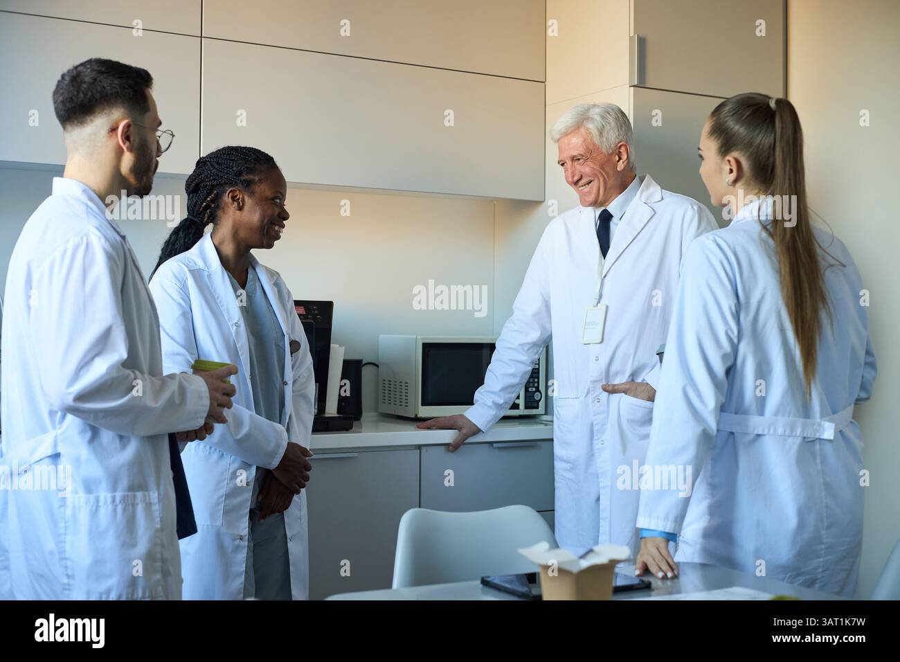 Medical professionals gathered in hospital break room, engaging in ...