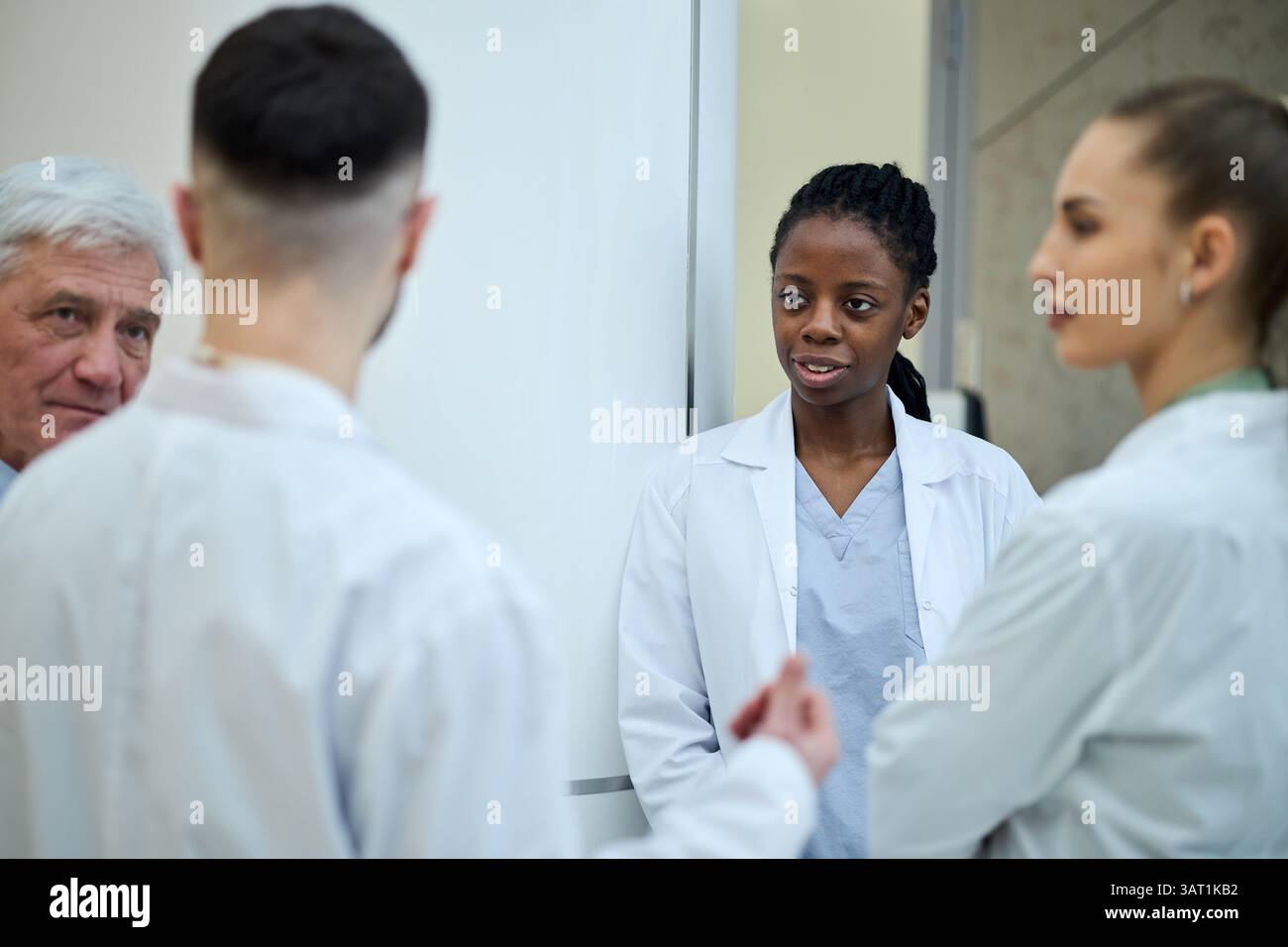 Multi-ethnic group of doctors discussing patient treatment plan in ...