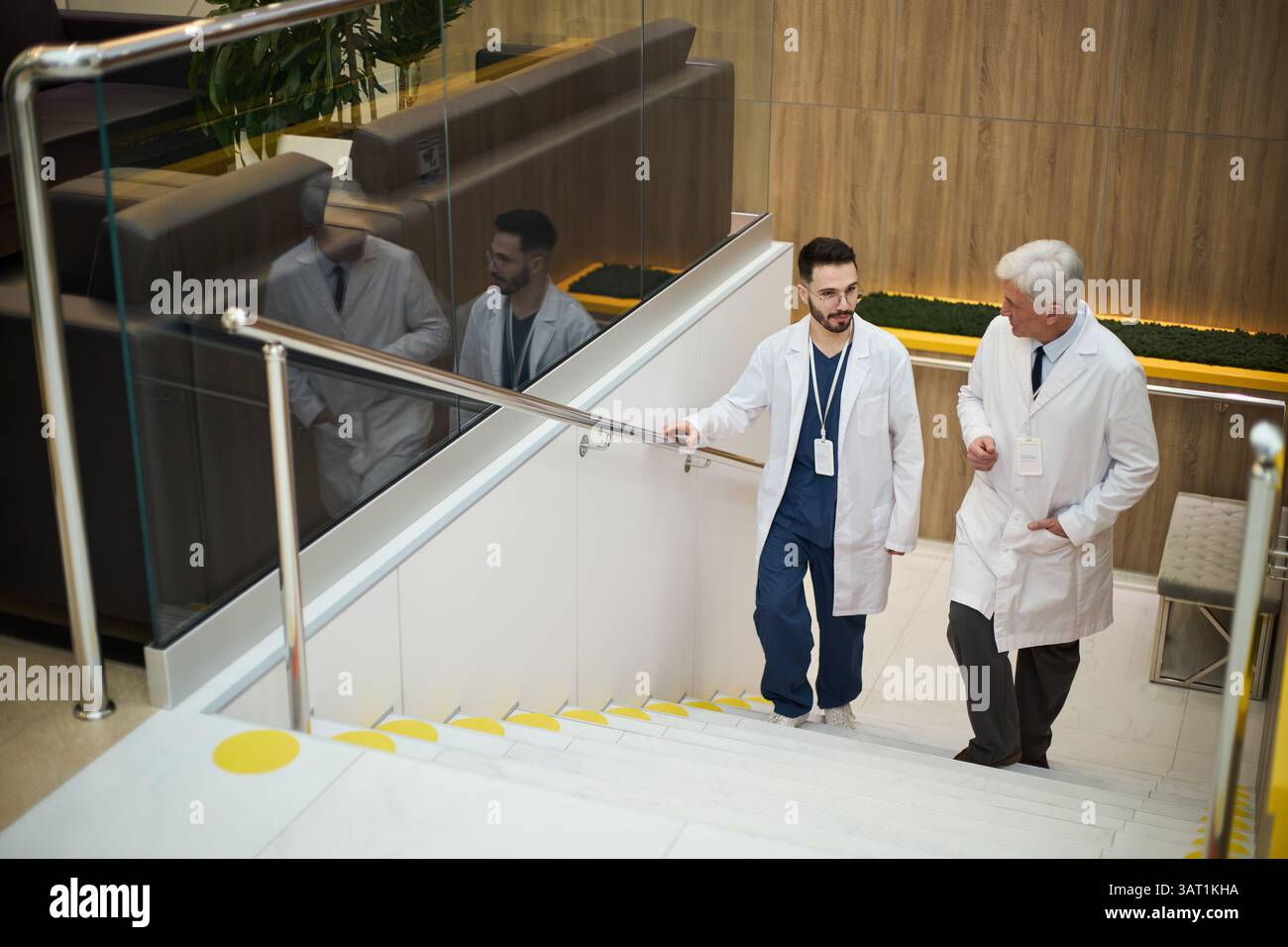 Two doctors walking up hospital stairs while conversing about patient ...