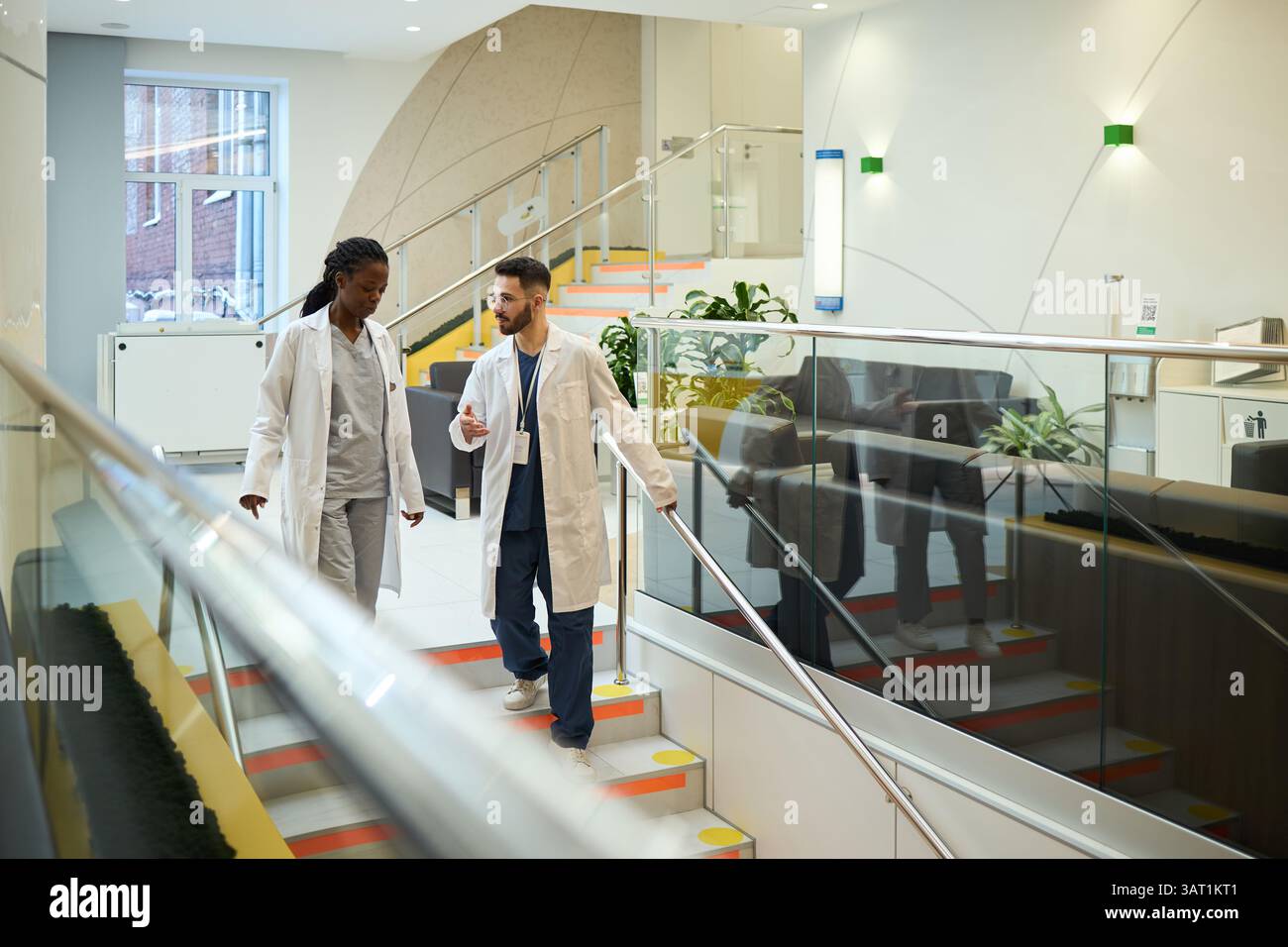 Two medical professionals conversing while walking down stairs in ...