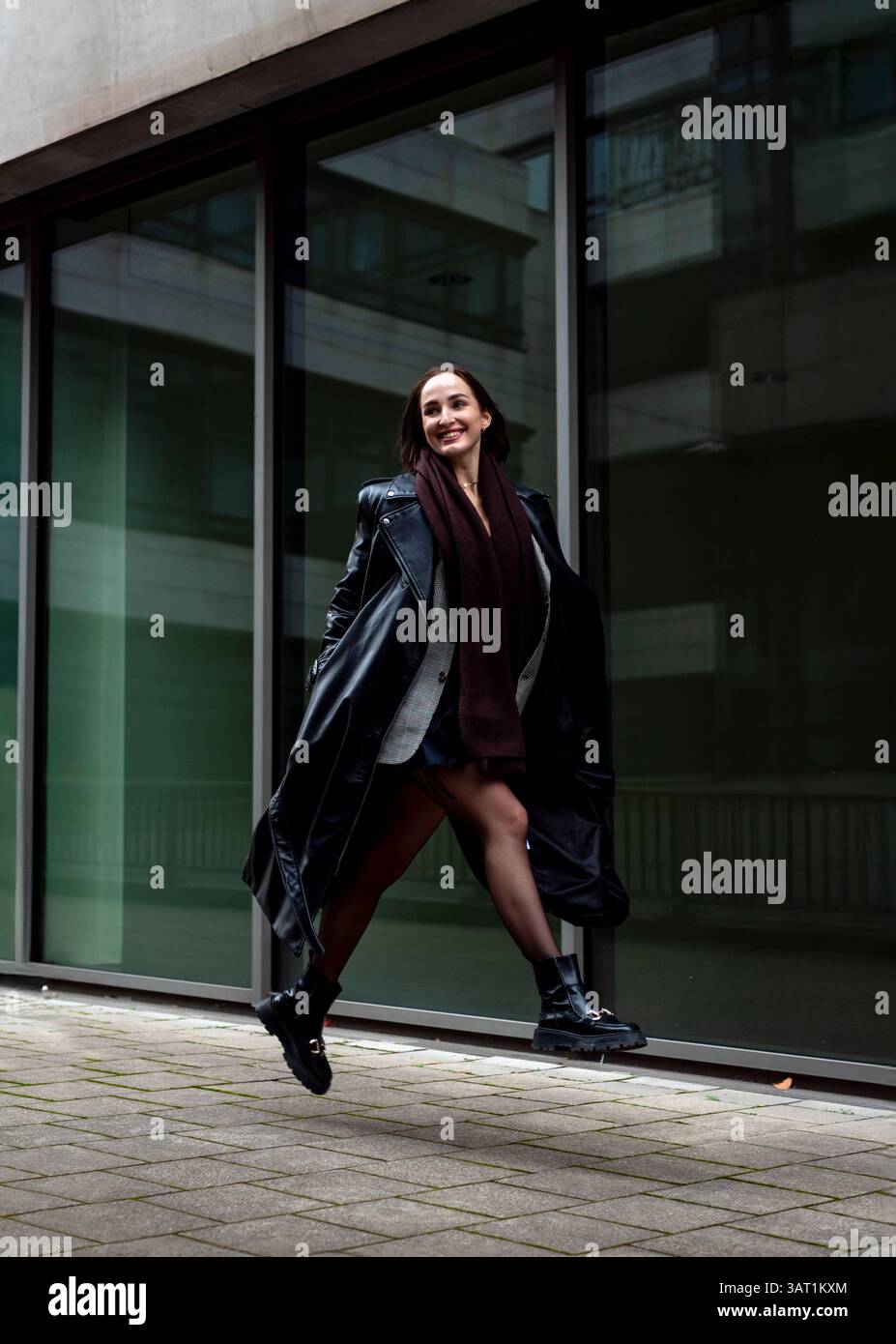 Gen Z woman running and jumping in front of an office building in ...