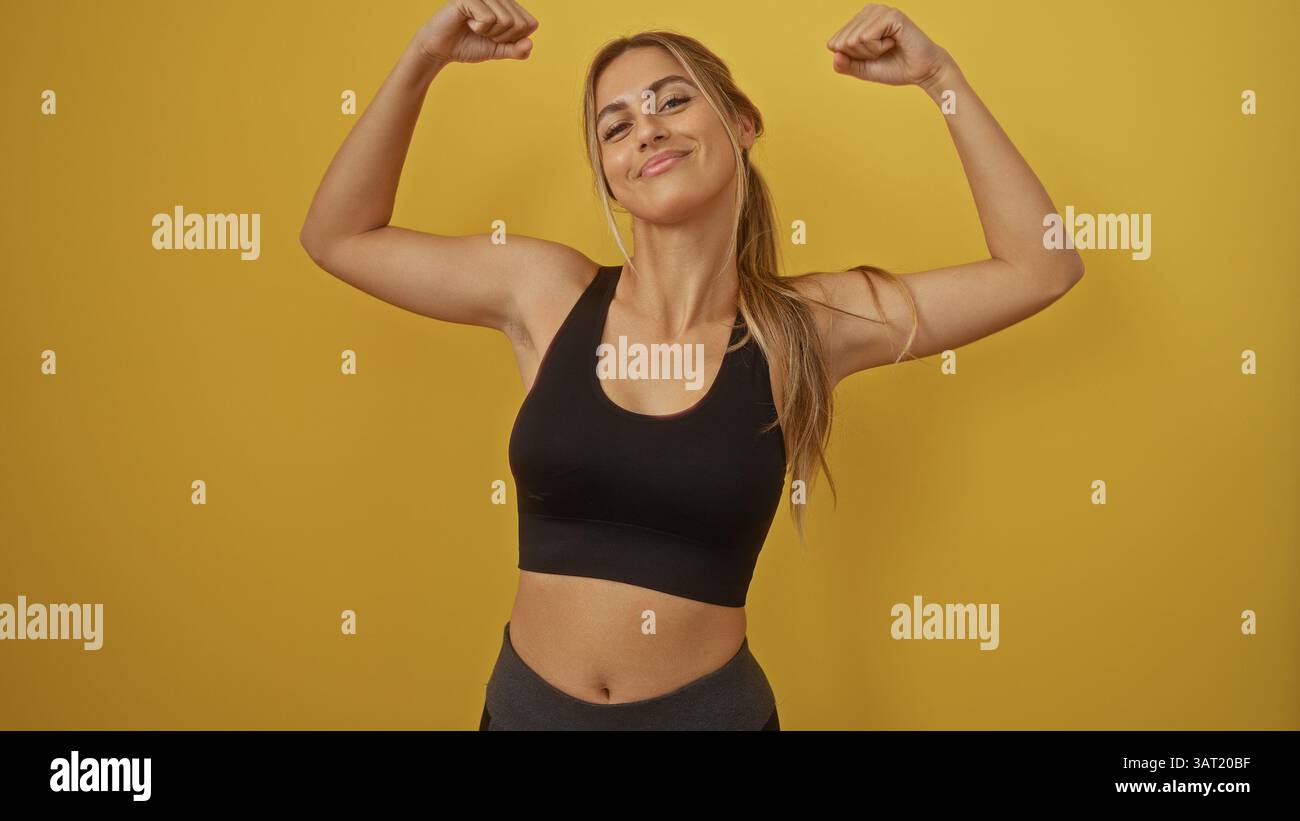 Woman flexing muscles confidently against bright yellow background ...