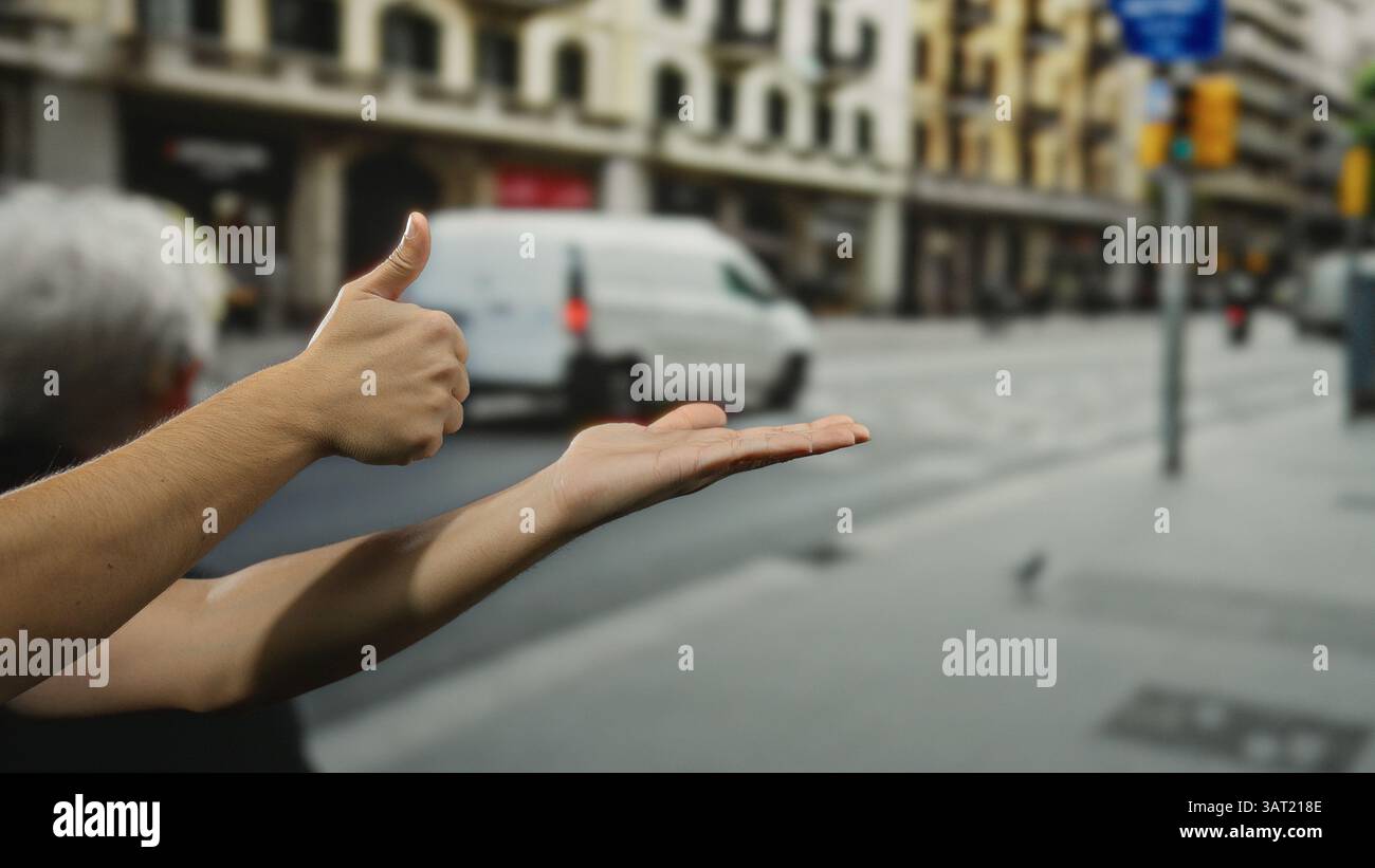 Hand gestures from a man on a city street with blurred urban background ...