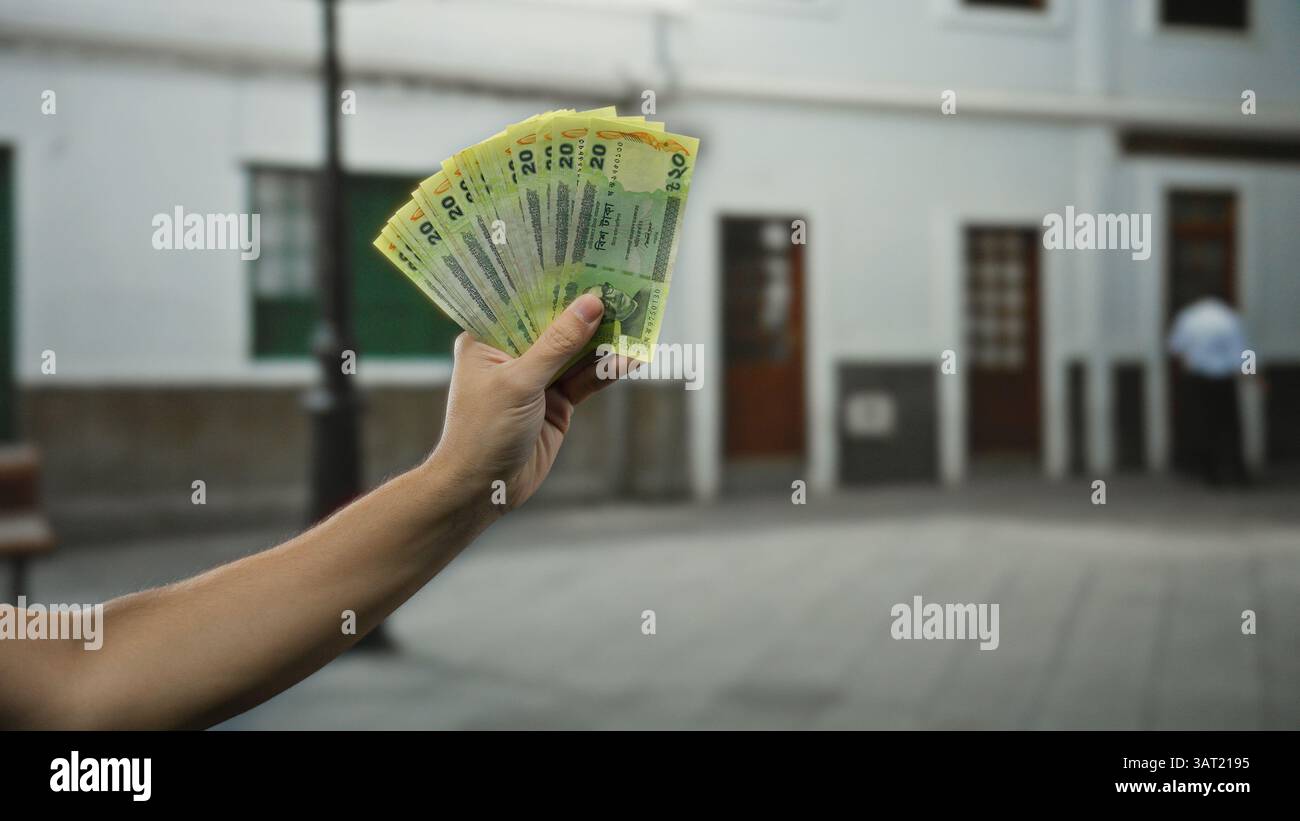 Man holding bangladeshi taka banknotes in hand outdoors on a city ...