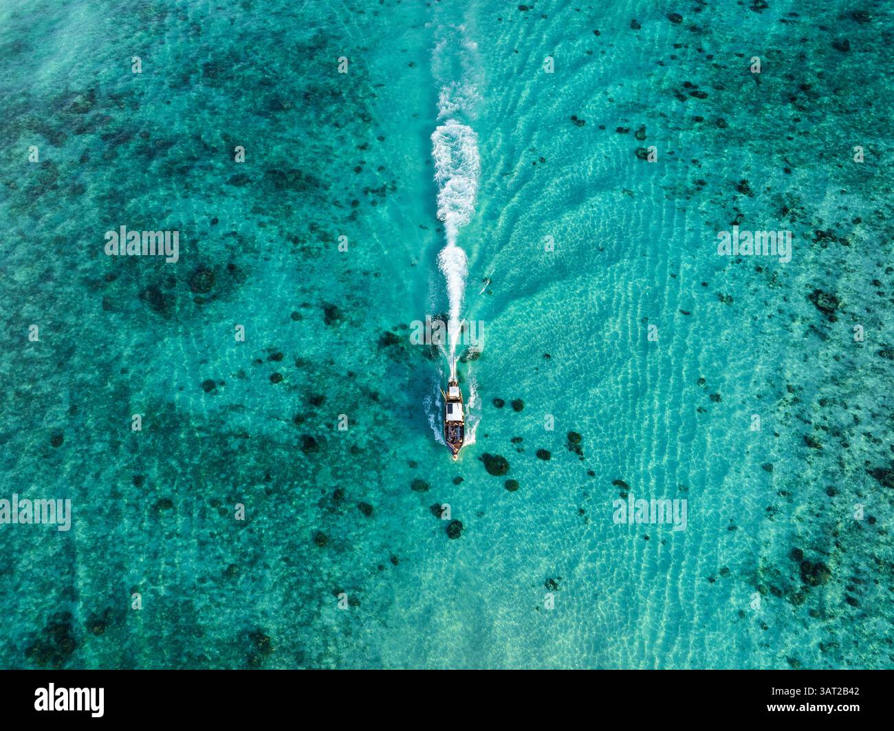Boat cruising through turquoise waters with white wake trailing behind ...