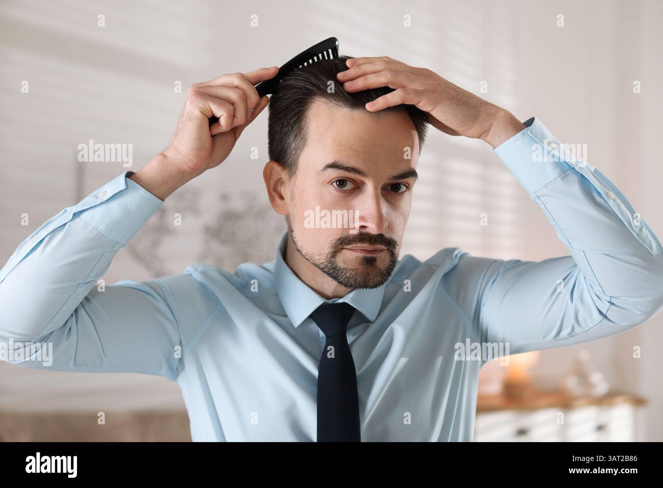 Handsome man combing his hair at home Stock Photo - Alamy