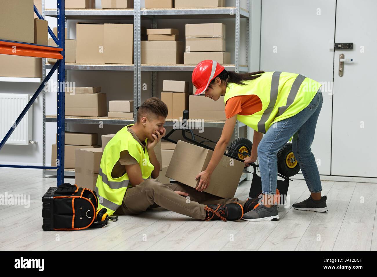 Accident at work. Woman helping her injured colleague in warehouse ...