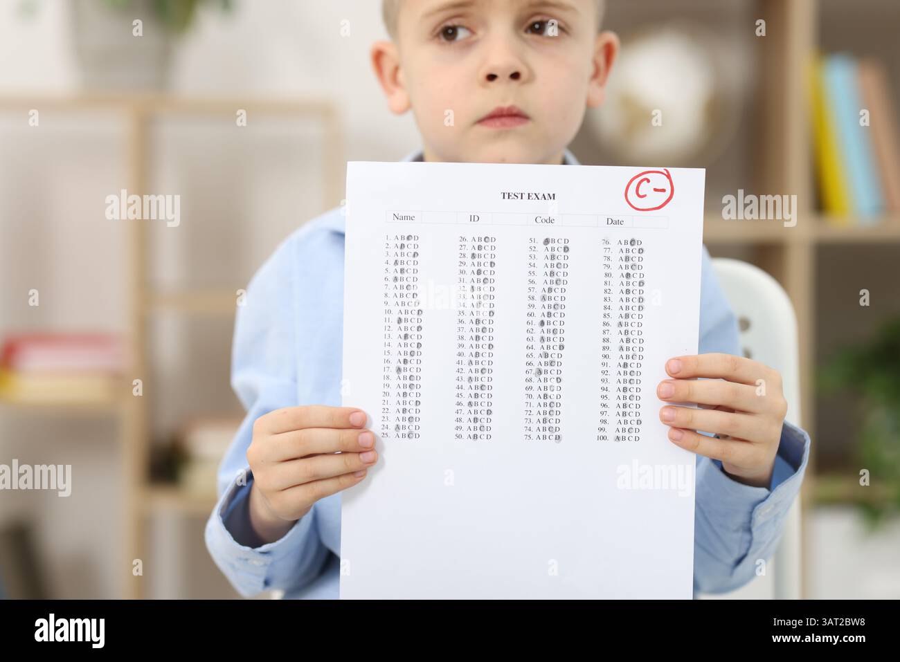 School grade. Sad boy holding answer sheet with letter C and minus ...