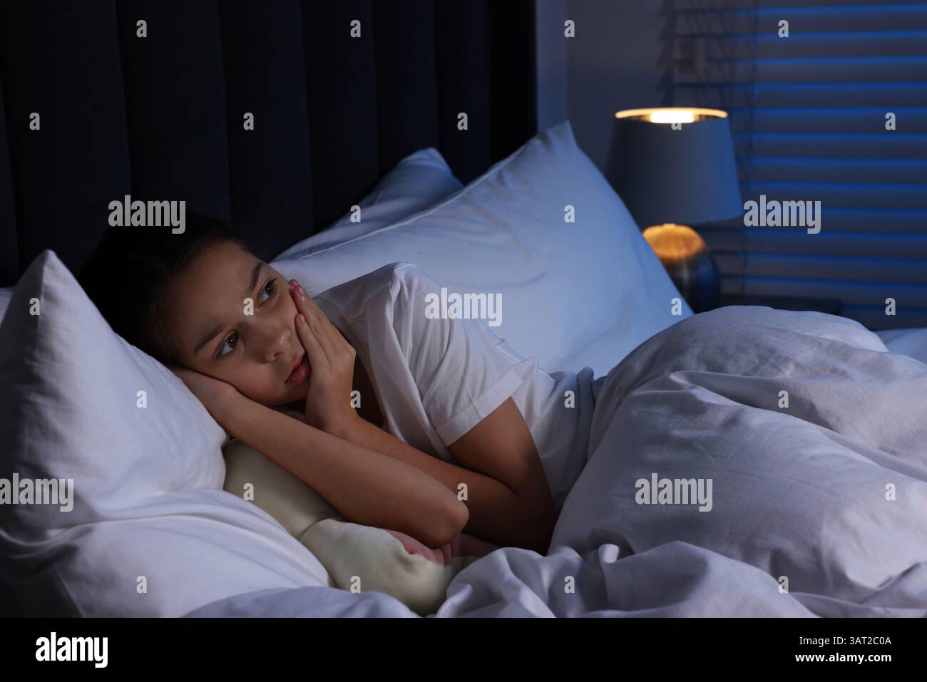 Scared girl lying in bed at night Stock Photo - Alamy