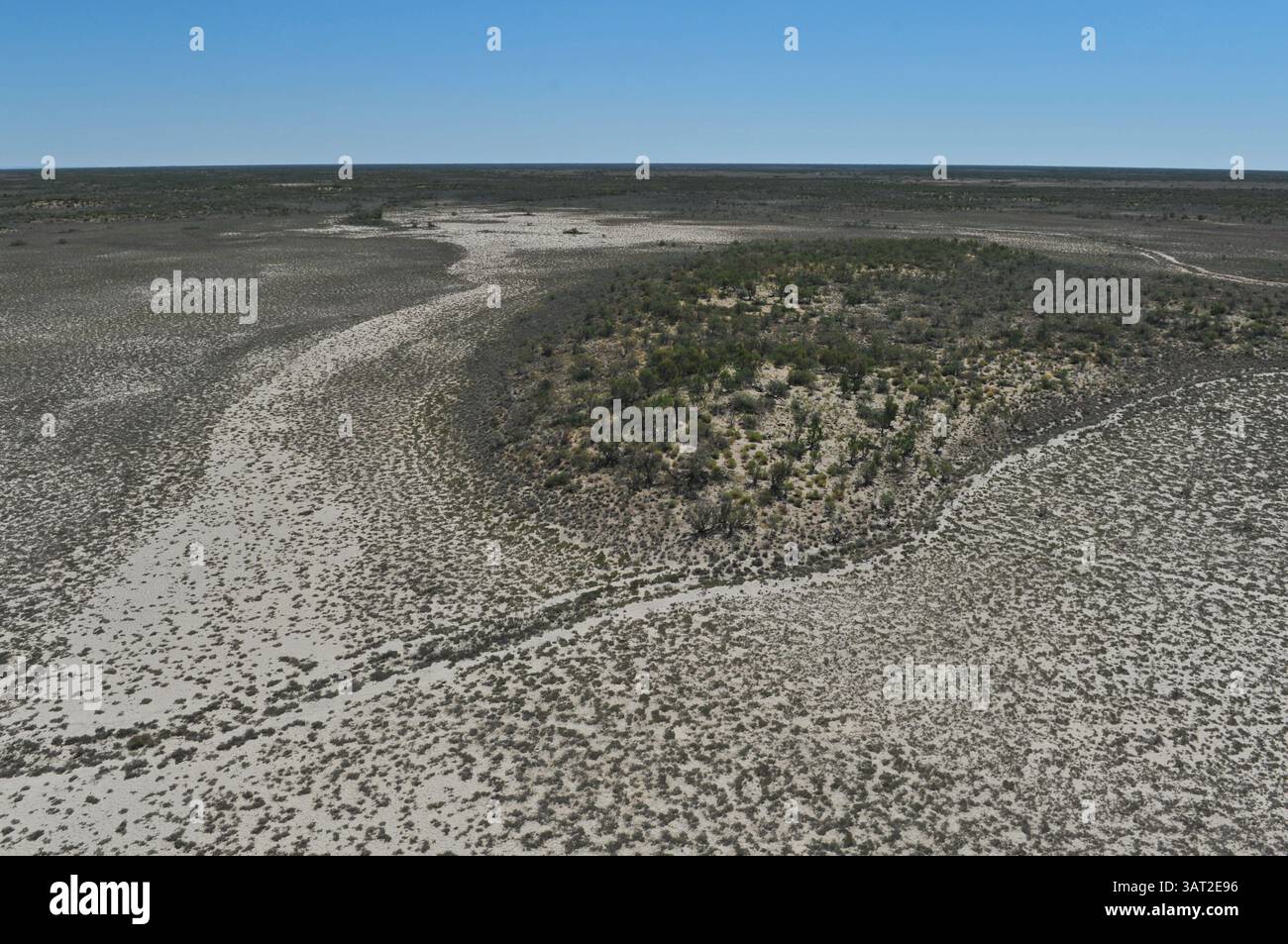 The road runs along a wide valley with sandy and rocky ground, grass ...