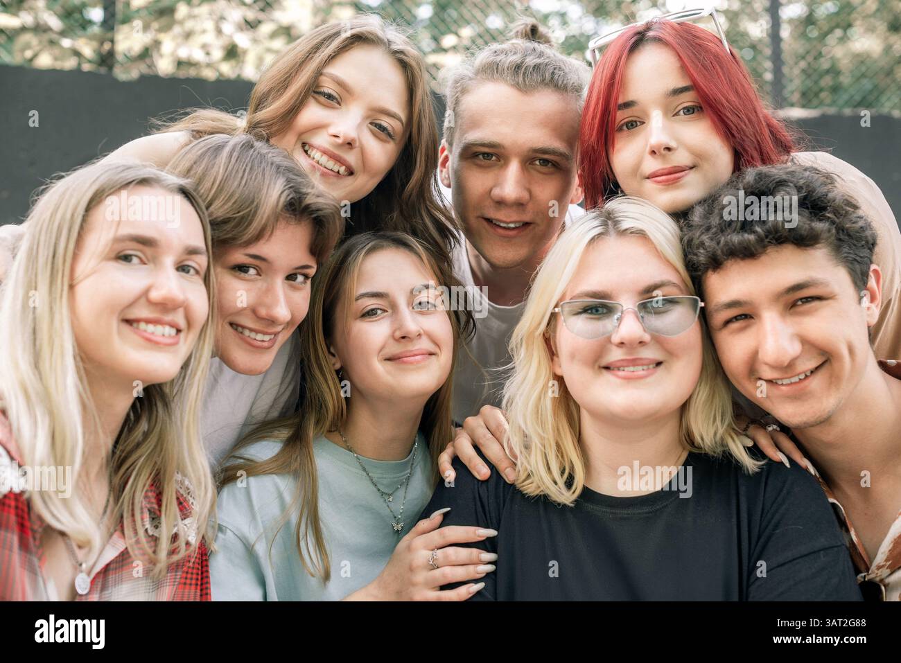 A diverse group of young friends smiling closely, showing unity ...
