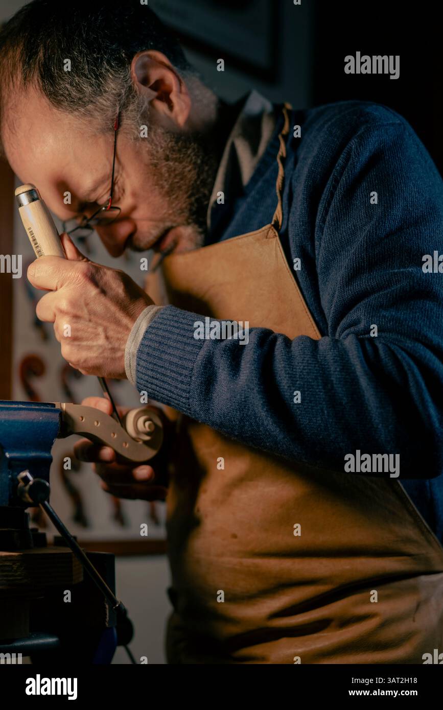 Skilled craftsman carving delicate wooden violin scroll Stock Photo - Alamy