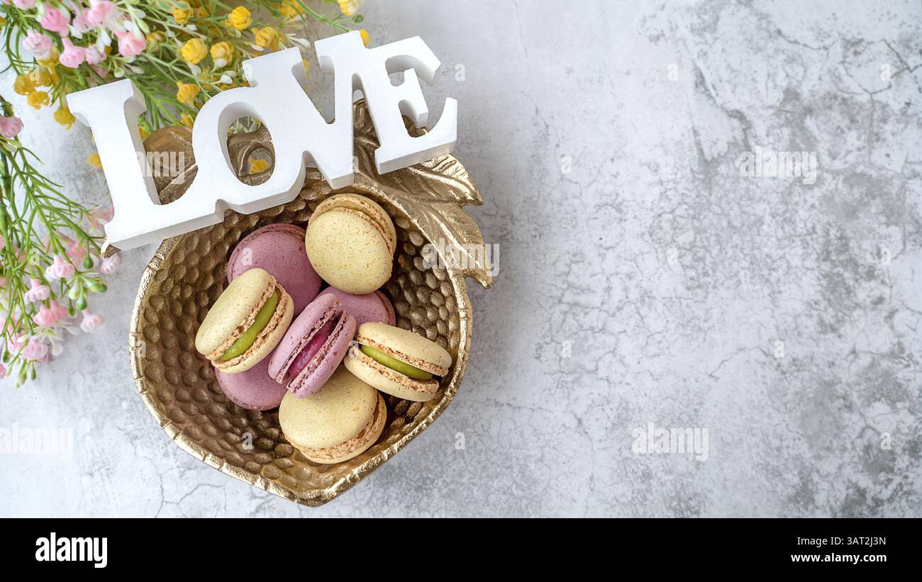 Colorful macarons are elegantly placed in a gold leaf bowl, accompanied ...